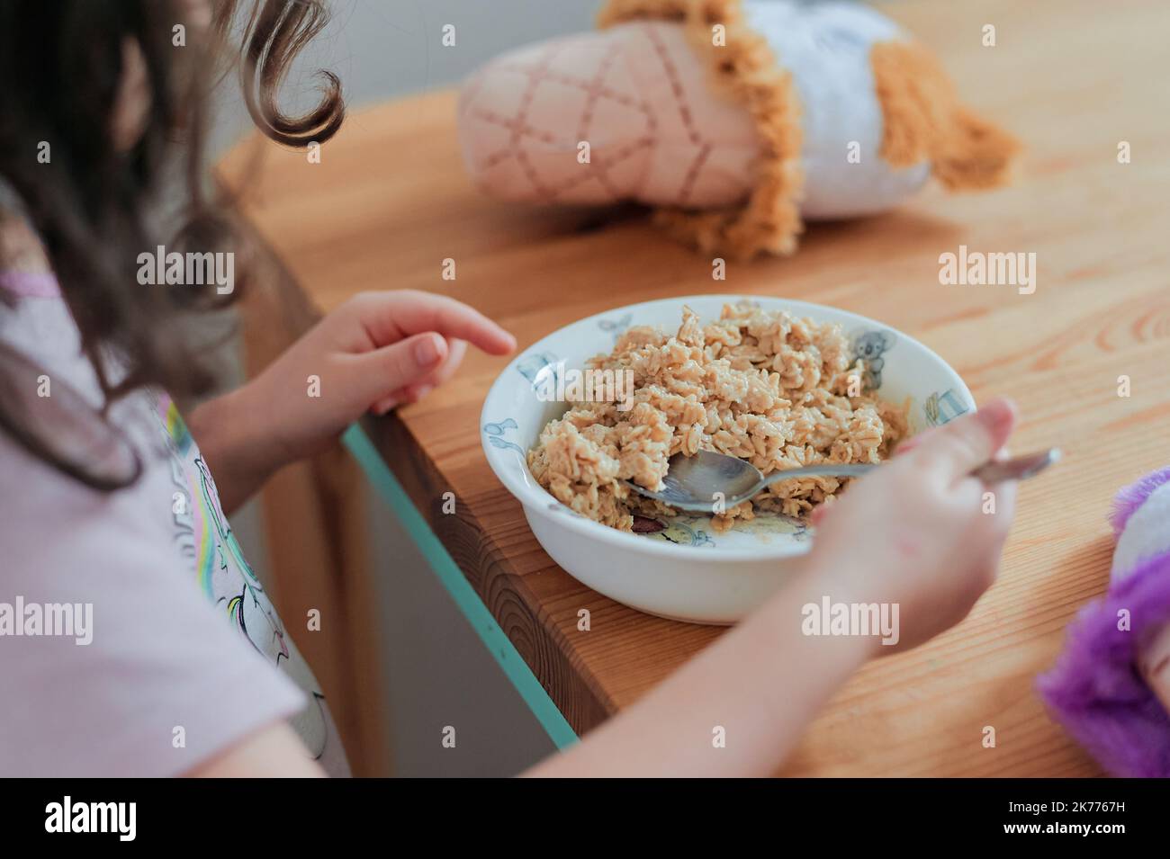a girl is eating oatmeal breakfast at the kitchen table Stock Photo - Alamy