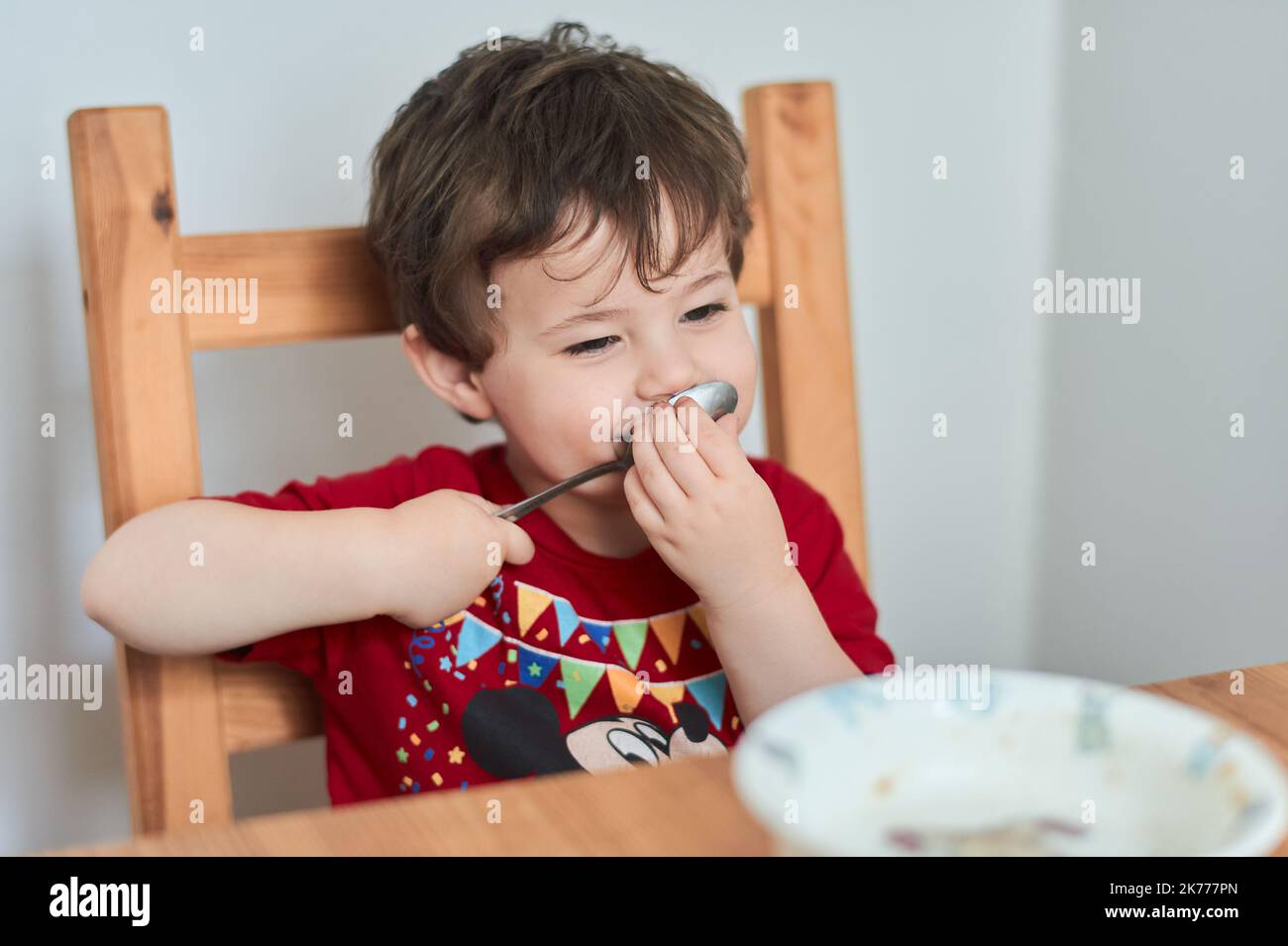 a boy is having fun at the breakfast table eating oatmeal Stock Photo ...