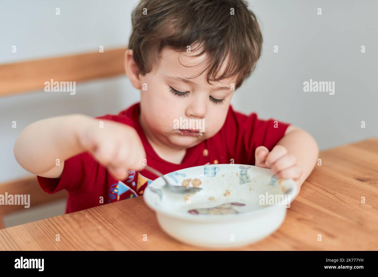 a boy is having fun at the breakfast table eating oatmeal Stock Photo ...