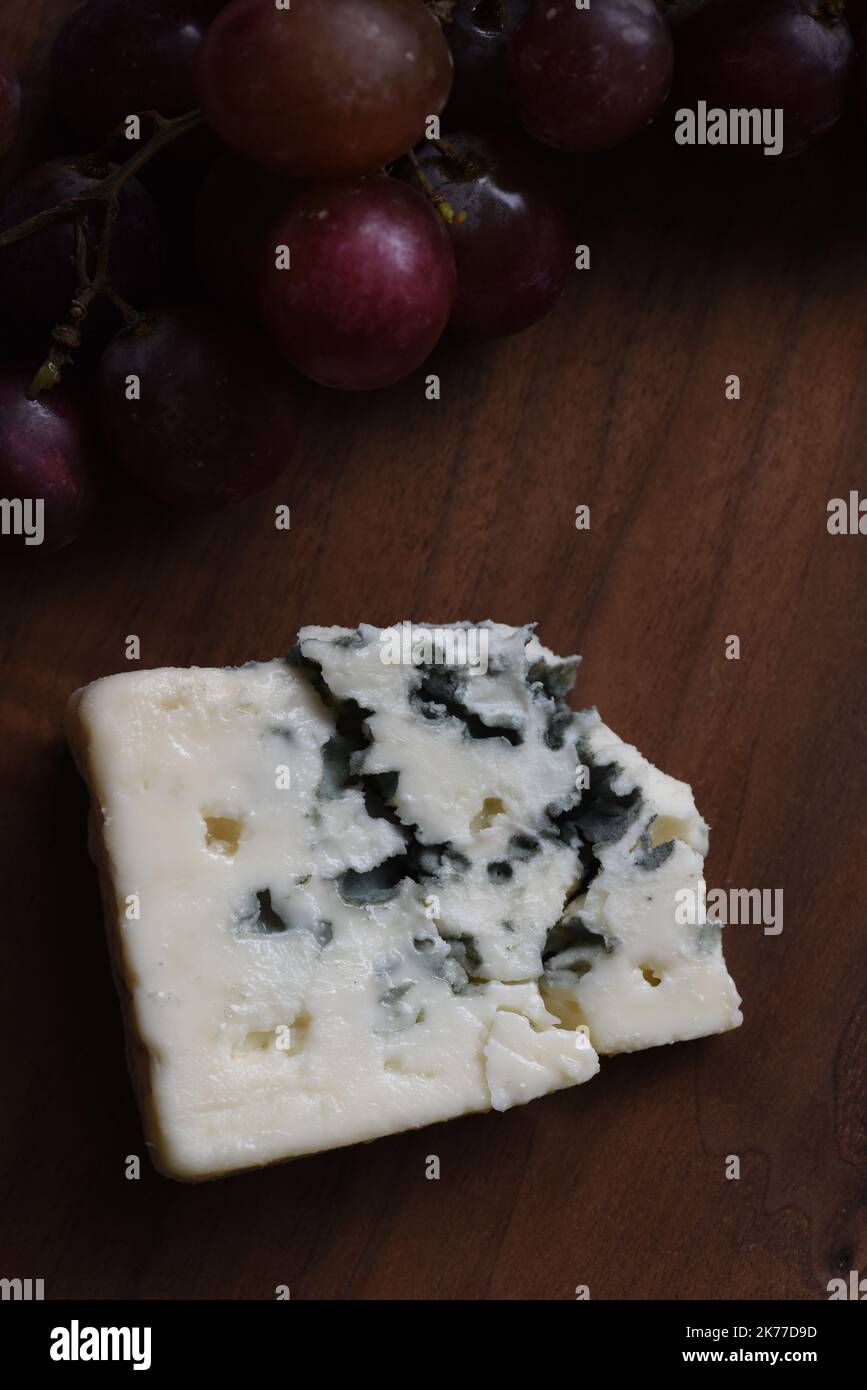 Blue cheese with purple grapes on a wooden serving board Stock Photo ...
