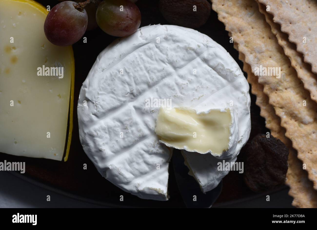 Gouda cheese, left, and a wheel of brie cheese with purple grapes and ...