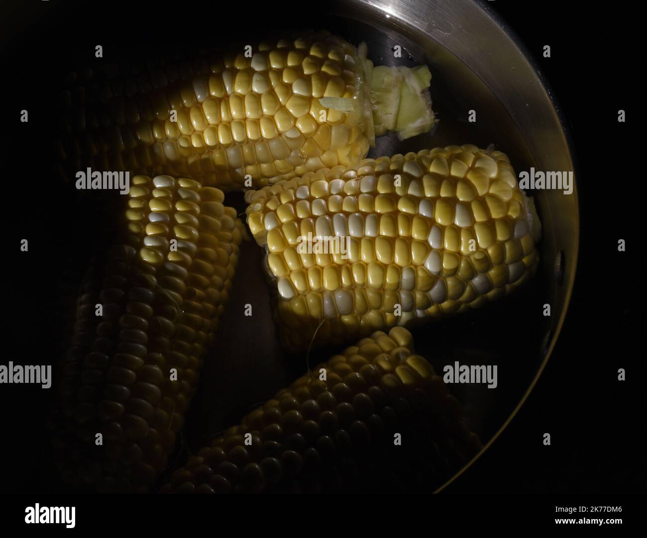 Broken pieces of fresh corn on the cob in a pot of water ready for ...