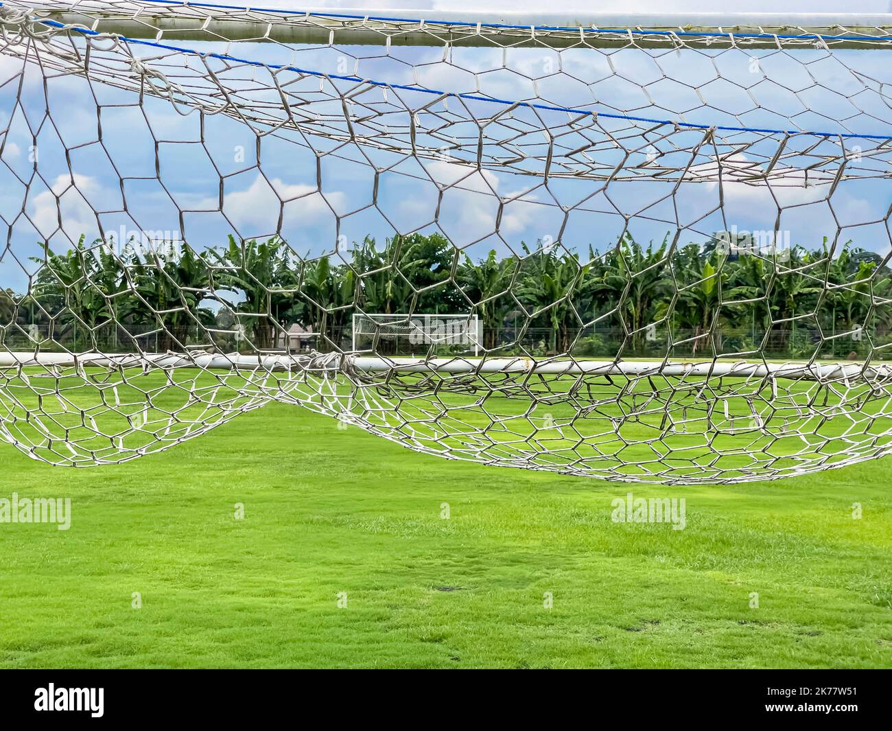 View through ootball gates net to large football field with green lawn ...
