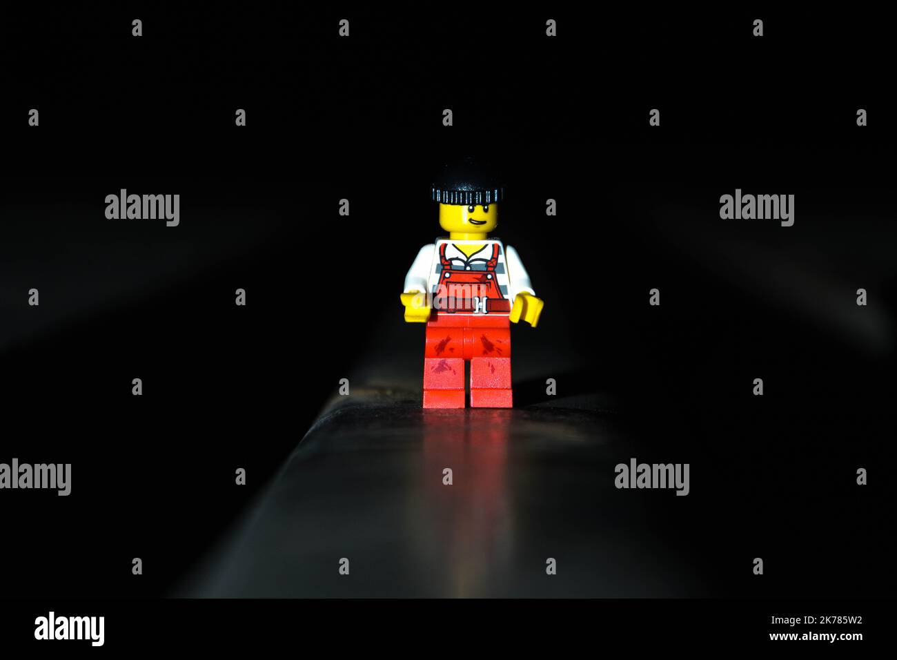 A front closeup Lego movie hero standing on a black surface with dark ...