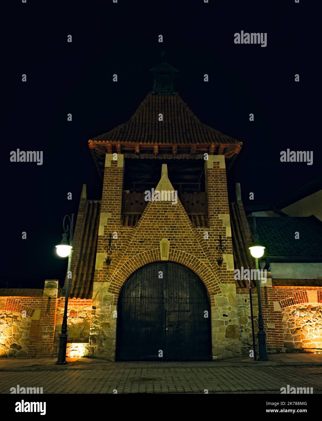 Illuminated stone wall at night with an alley with street lamps and a ...