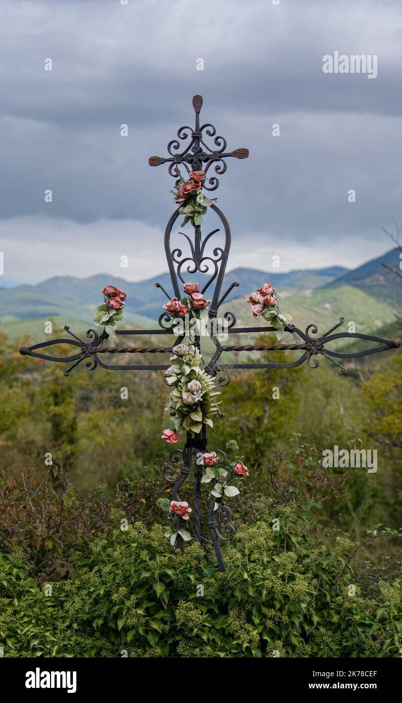 a wrought iron religious cross adorned with flowers small wreaths ...