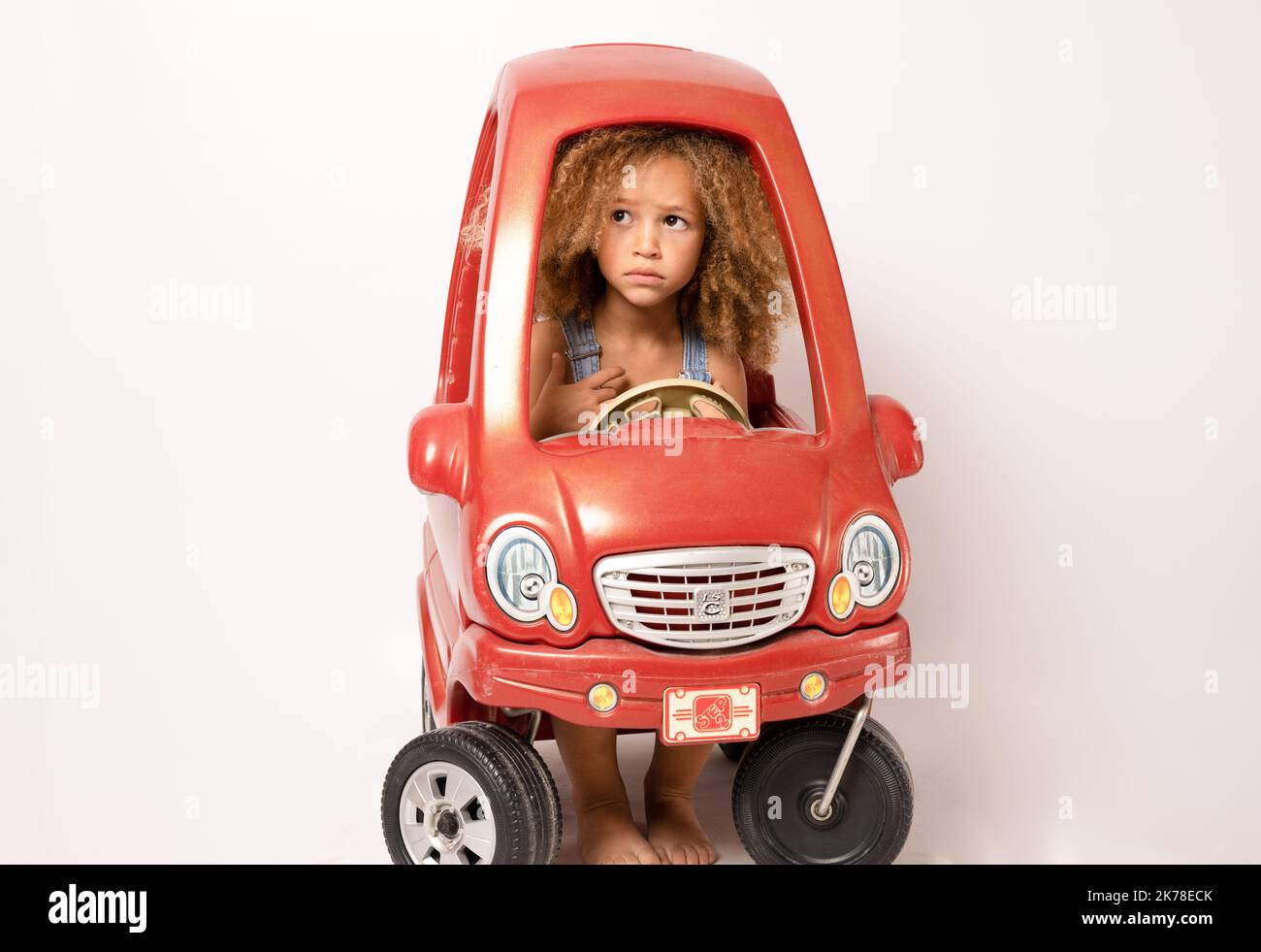 Cute little child girl driving children's electric toy car on white ...