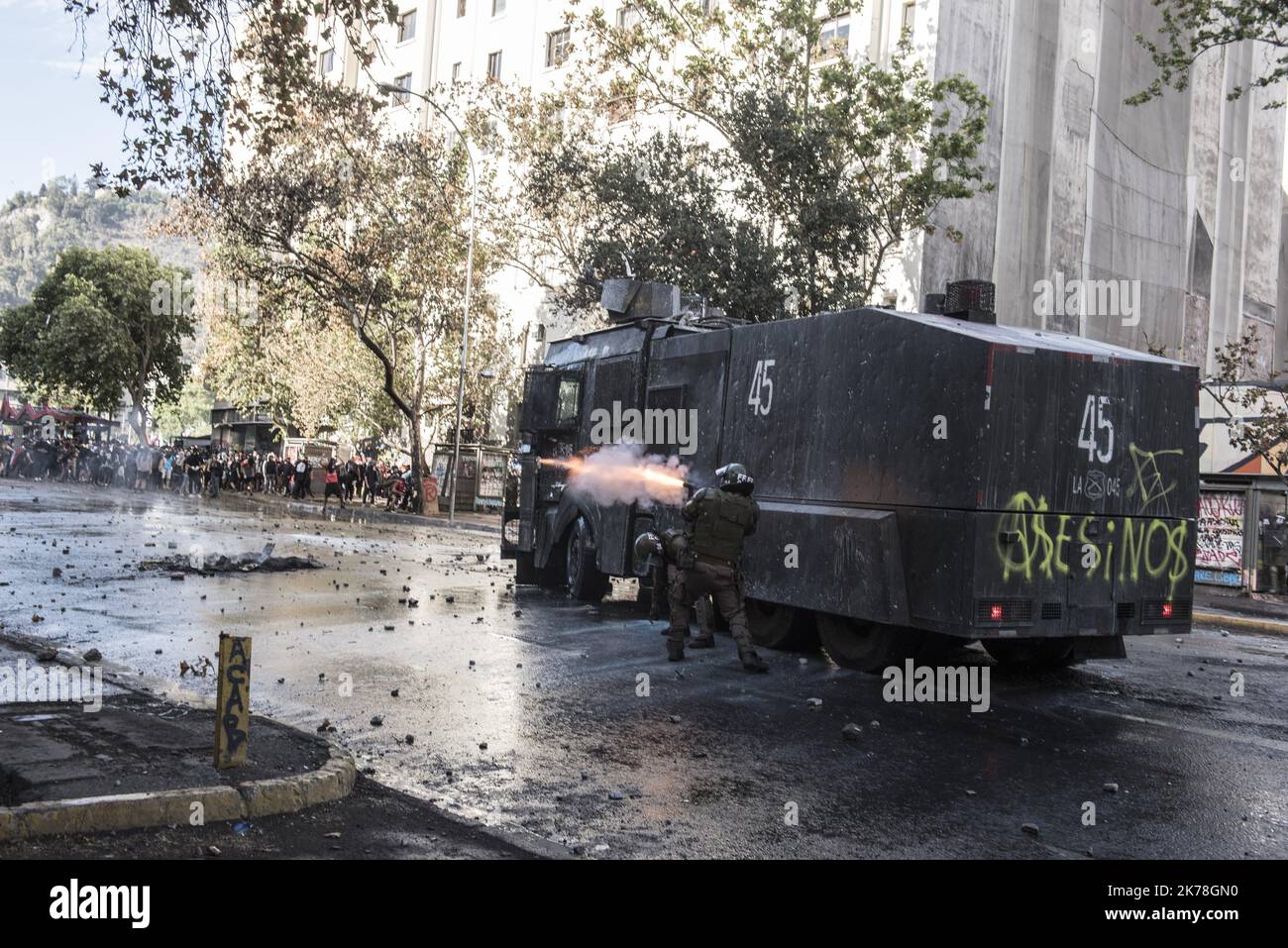 Tense shot of a rifle firing tear gas during a demonstration. Numerous ...