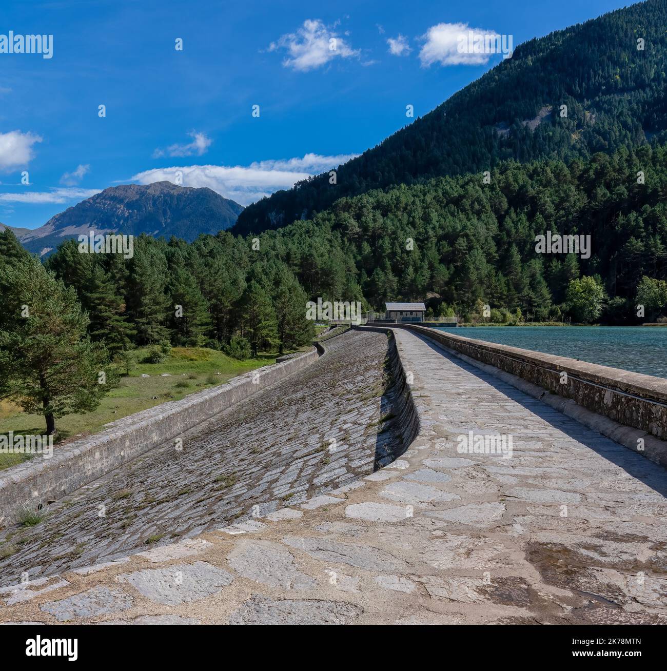 man-made aqua blue water reservoir to feed a mountain hydro power ...