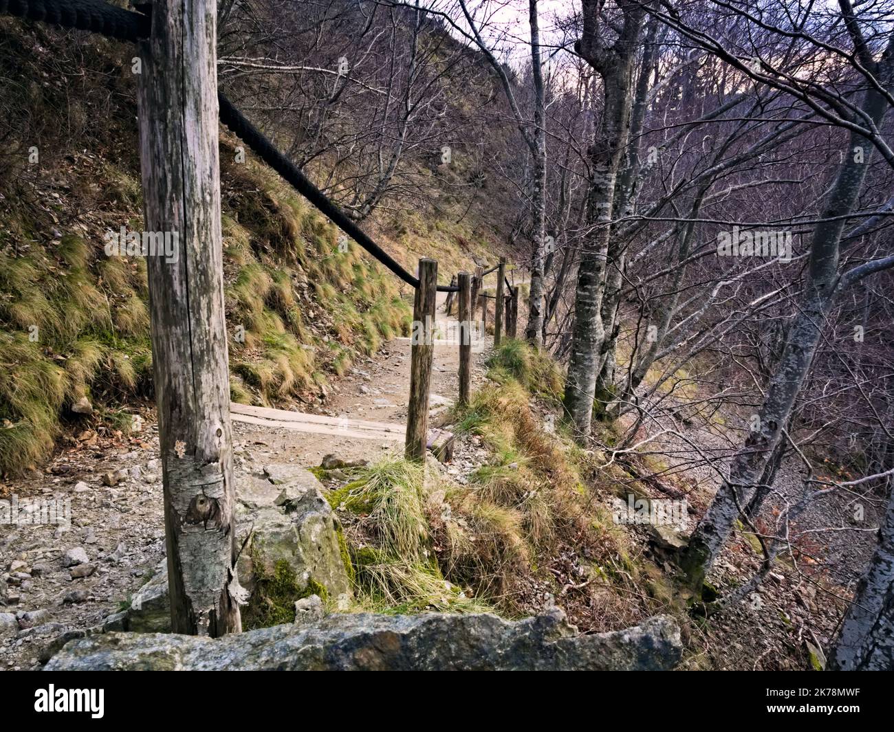 Mountain trail in the woods with a wooden railing on a rocky surface ...