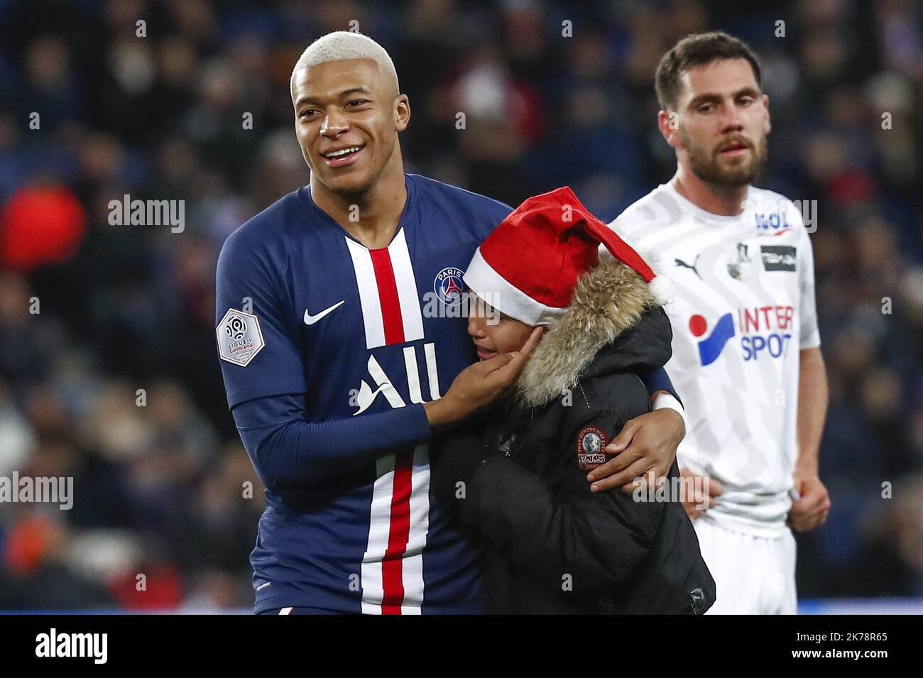 Paris Saint Germain's Kylian Mbappe hugs a young pitch invader (R ...