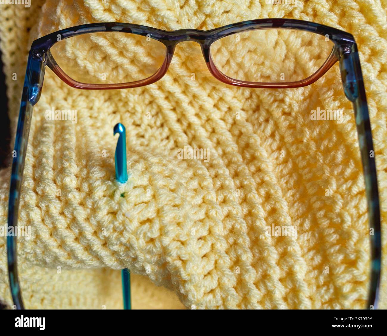 Knitting tools and glasses set on a backdrop of a wool knitting work in ...