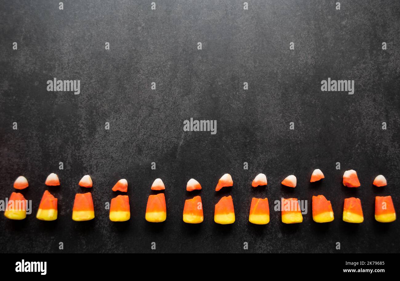 Broken candy corn look like small bad teeth. Black background. Copy ...