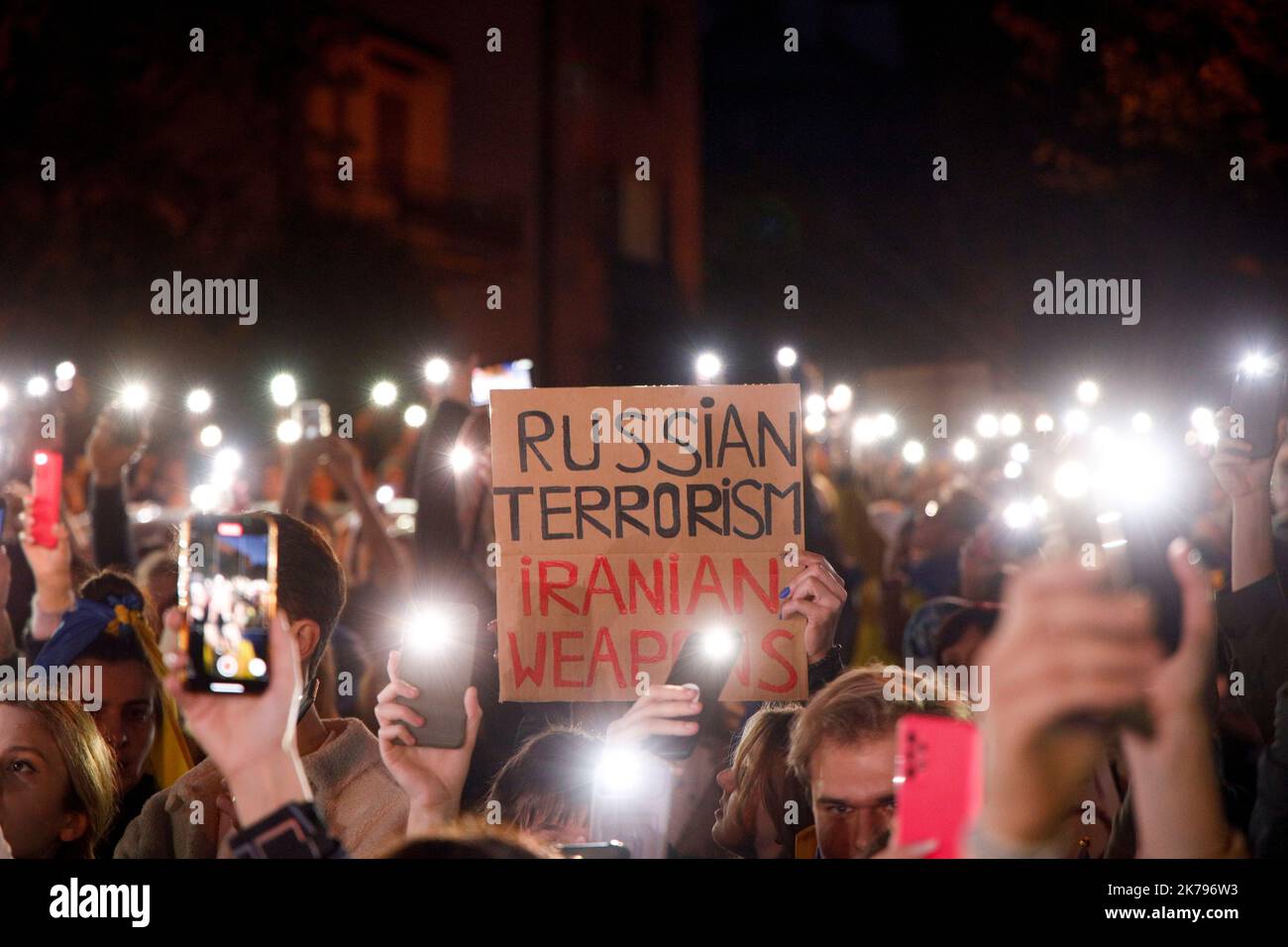 Protesters hold up their phones with flashlights lit during a protest ...