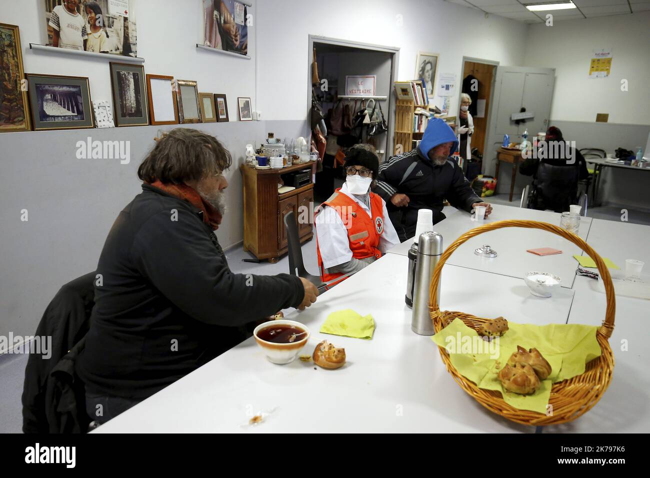 A member of the Red Cross sits with homeless people as they eat a meal ...
