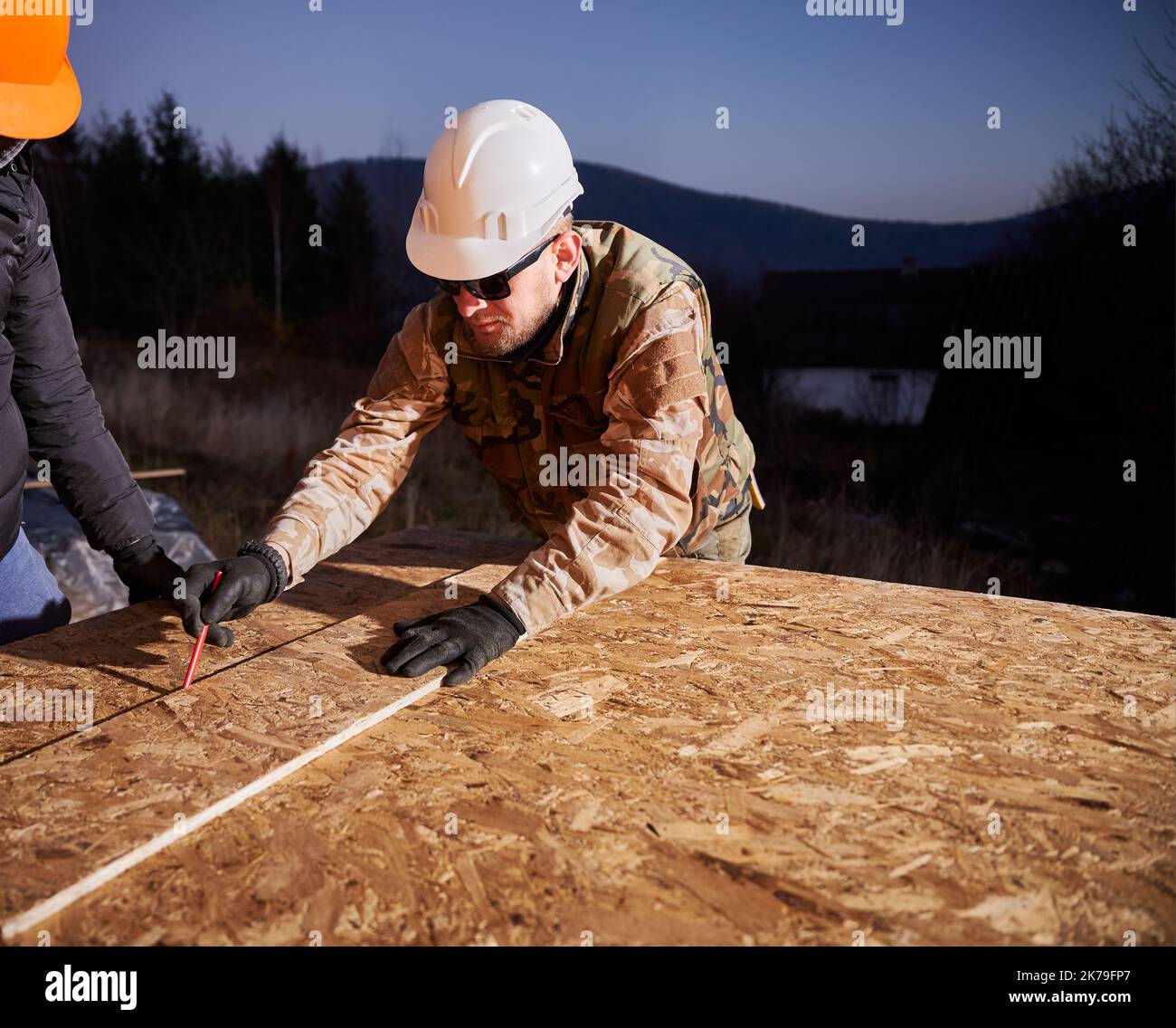 Man worker building wooden frame house. Carpenter measuring OSB sheet ...