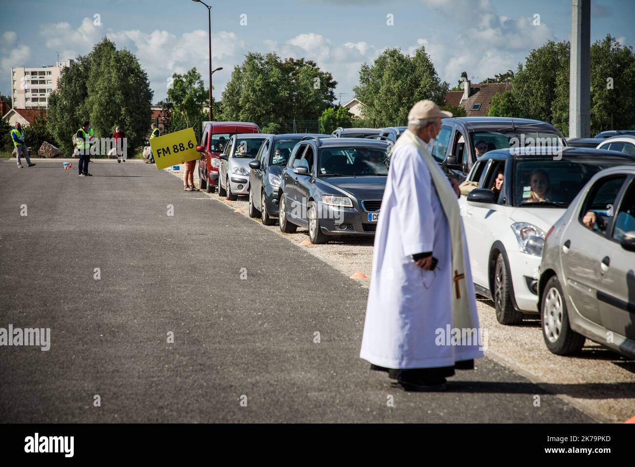 A priest talks with worshipers in a car prior to the celebration of the ...