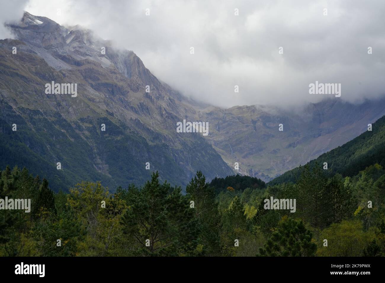 view along a glacial forest lined valley to a massive mountainous ...