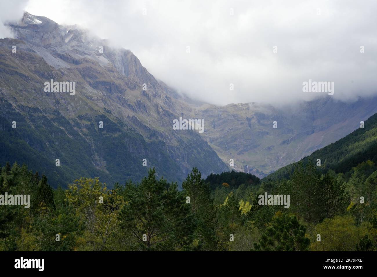 view along a glacial forest lined valley to a massive mountainous ...