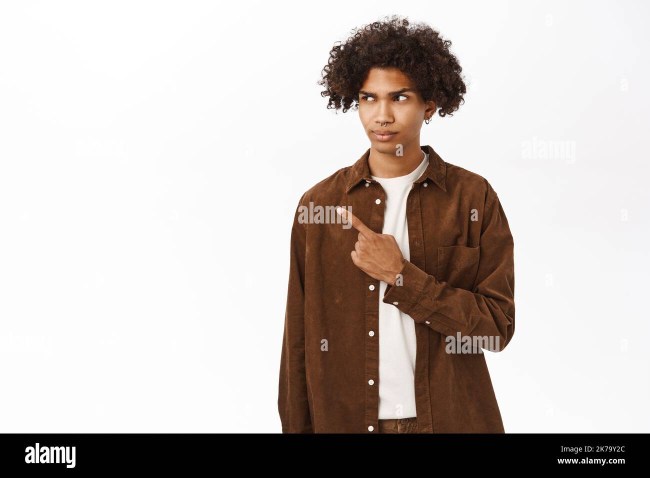 Portrait of skeptical young man, pointing and looking left, staring ...