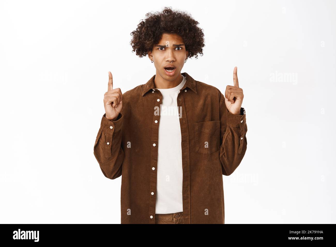 Shocked guy pointing fingers up, looks worried and concerned, stands ...