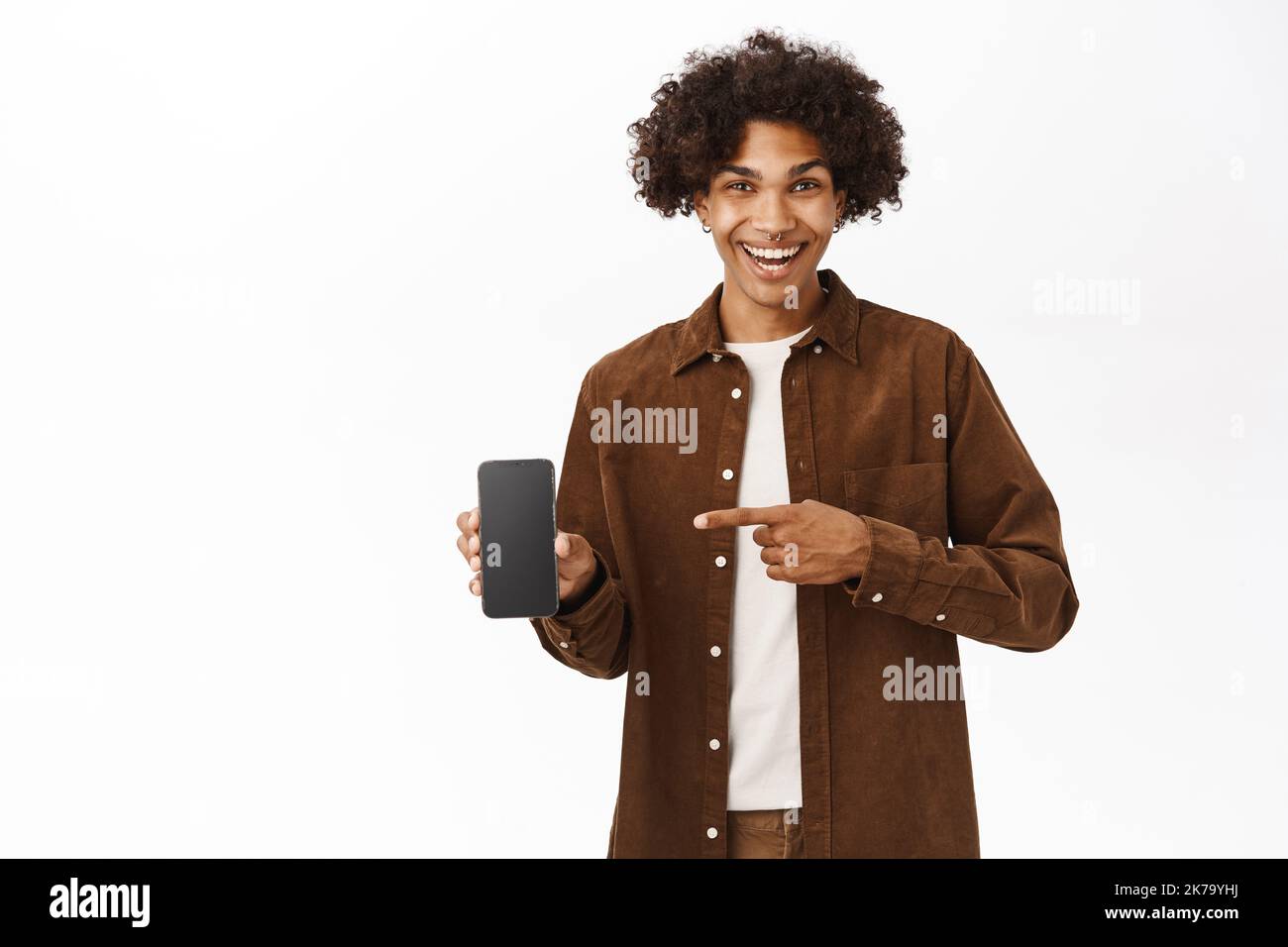 Portrait of handsome smiling guy, pointing finger at smartphone screen ...