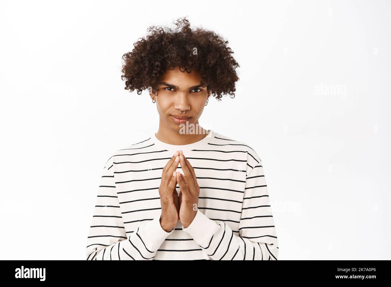 Close up of sly young man, scheming, has plan, steeple fingers and ...