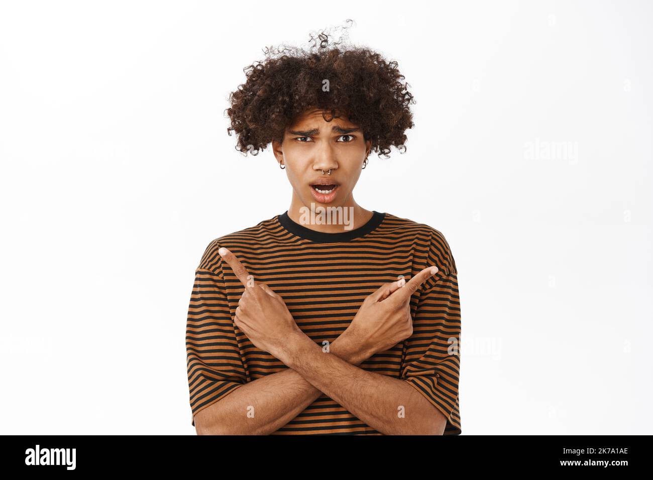 Portrait of young guy with confused face pointing sideways, cant decide ...