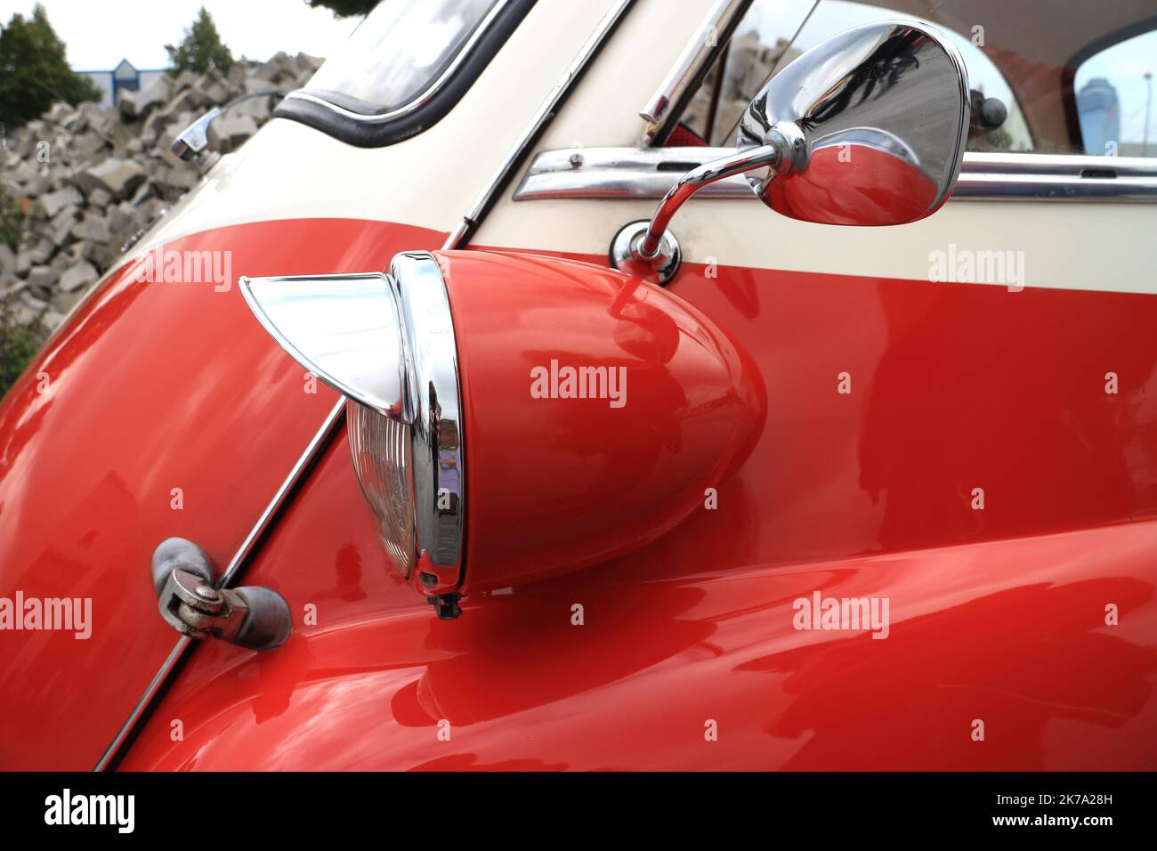 Detail of a small red vintage car with headlight and sideview mirror ...