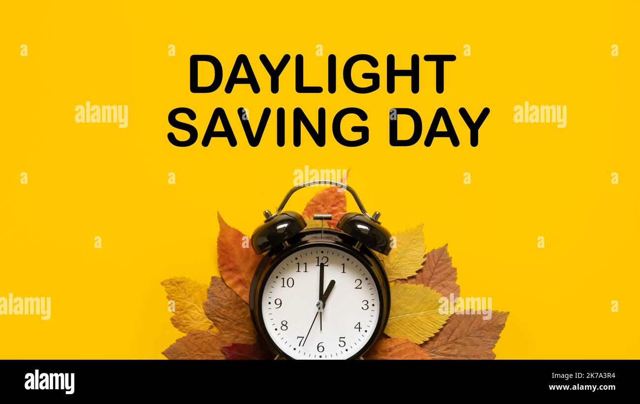 Daylight saving day. Fall Back. Black Alarm clock and autumn leaves and ...