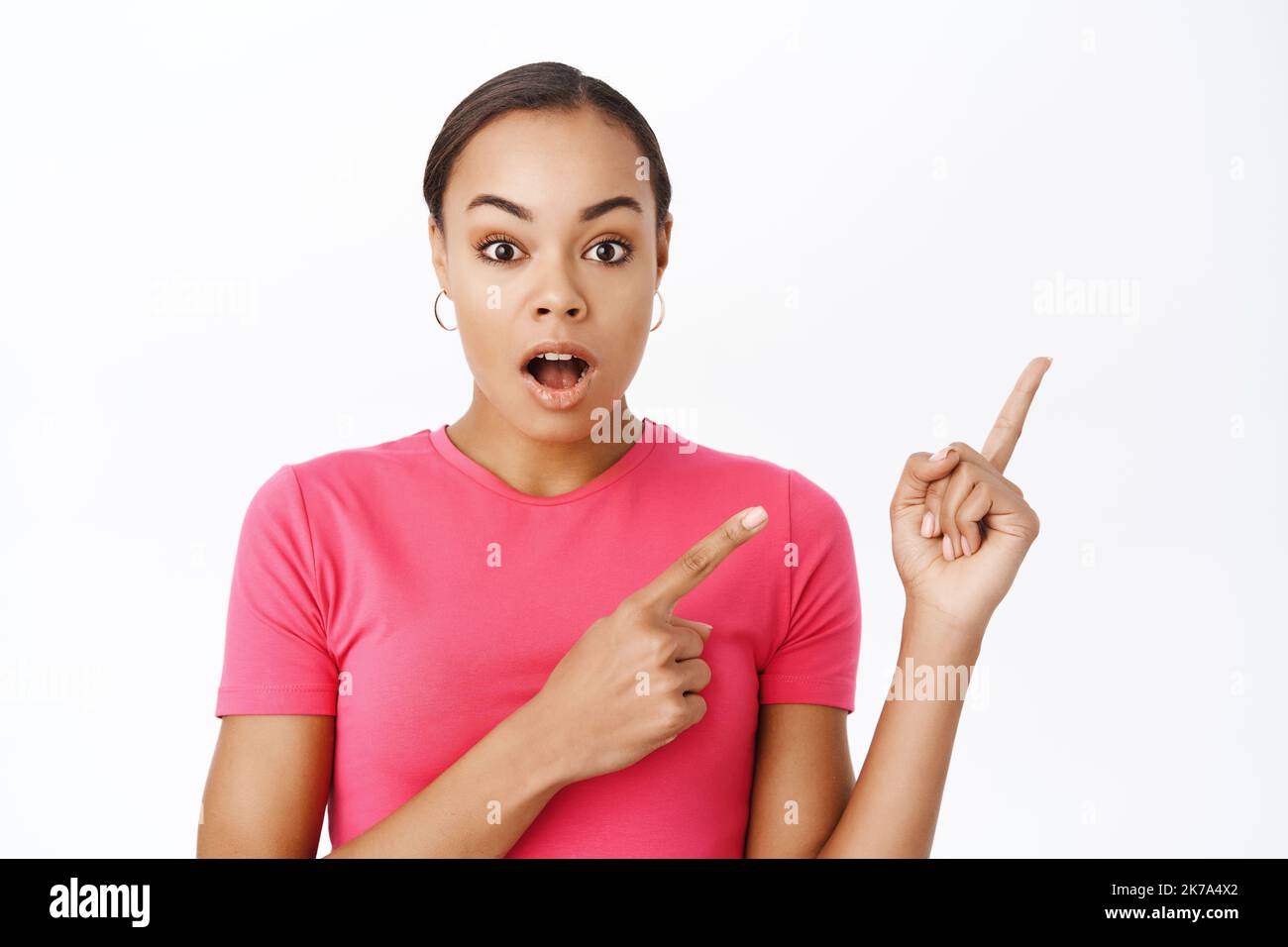 Close up of impressed female model, points finger right, gasps with wow ...