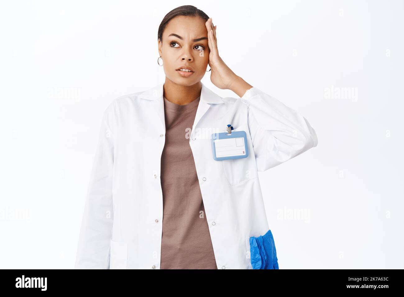 Troubled female doctor, holds hand on head, look concerned and ...