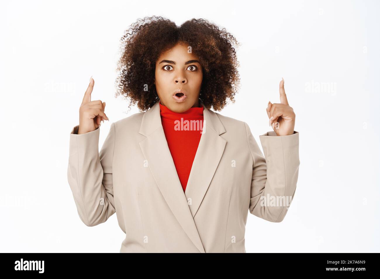 Portrait of surprised black woman, saleswoman pointing fingers up ...