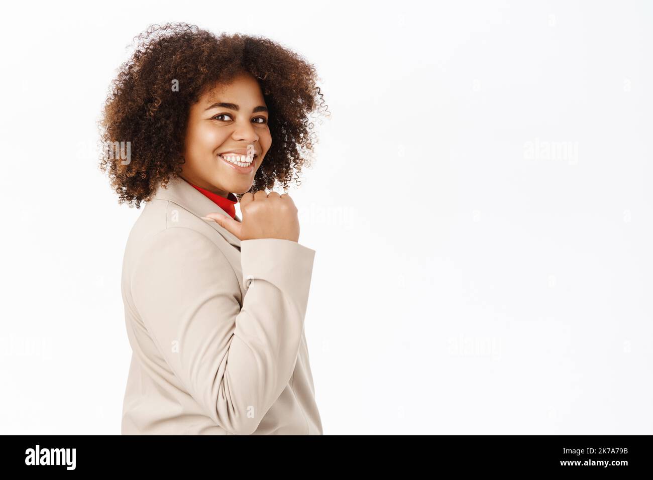 Smiling businesswoman points behind her shoulder at advertisement ...