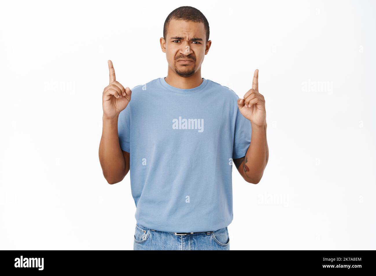 Upset man pointing fingers up, grimaces and looks disappointed, shows ...