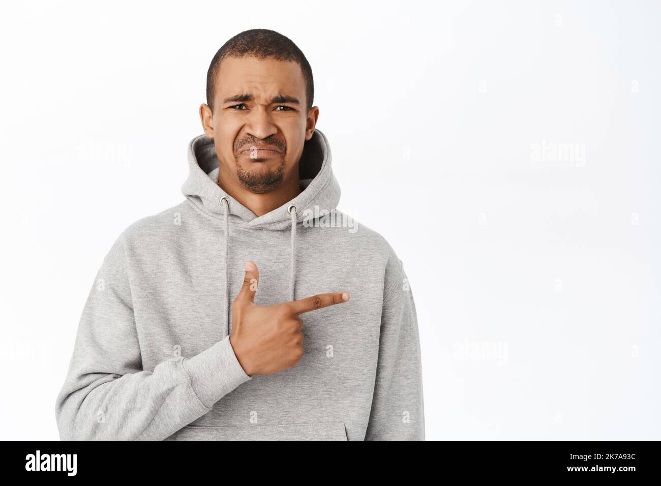 Upset, gloomy young man pointing right and crying, sulking from regret ...