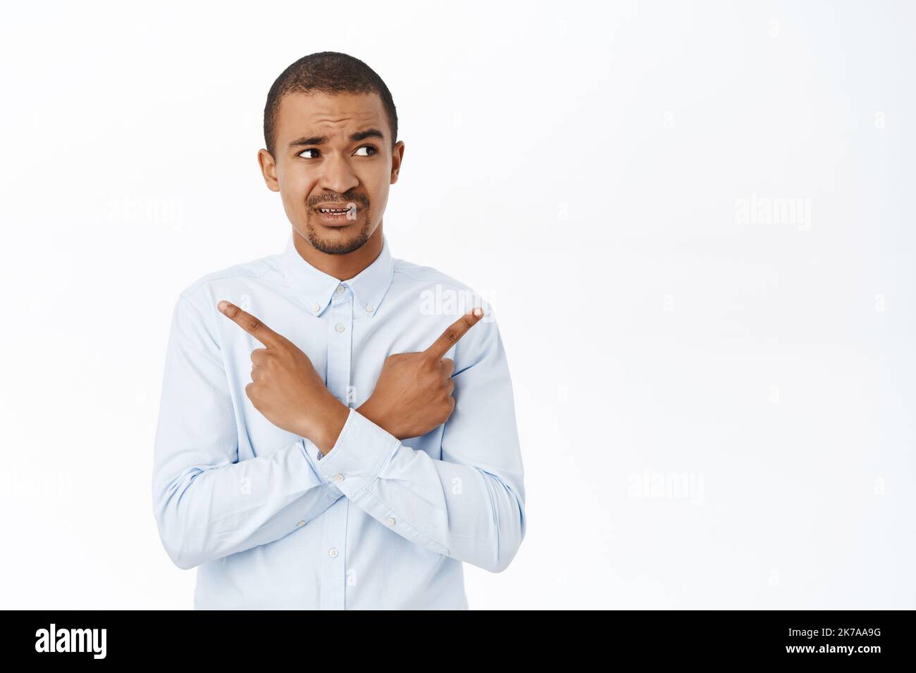 Portrait of confused office worker, young man pointing sideways, cannot ...