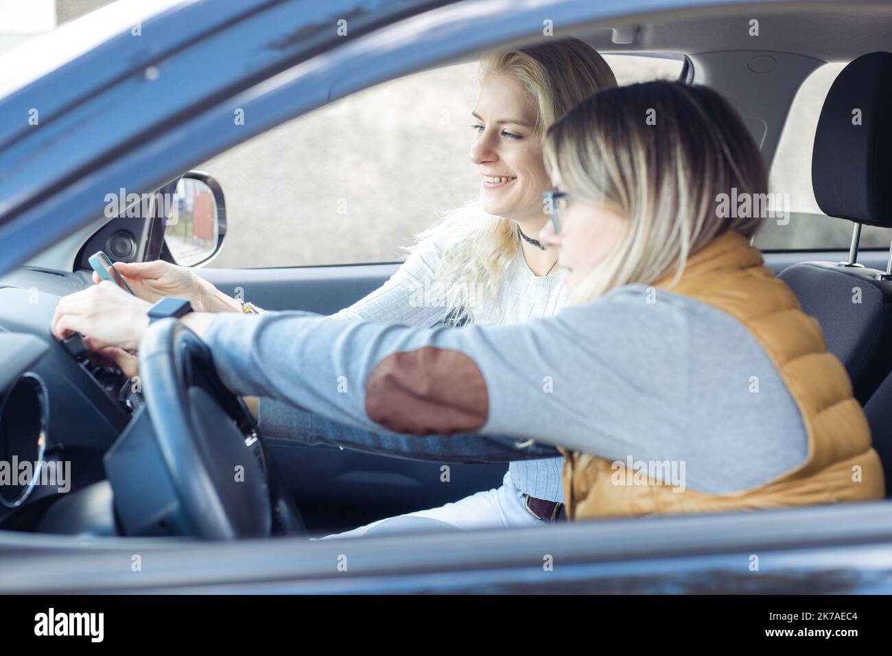 Joyful best friends together sit into car and place in salon phone ...
