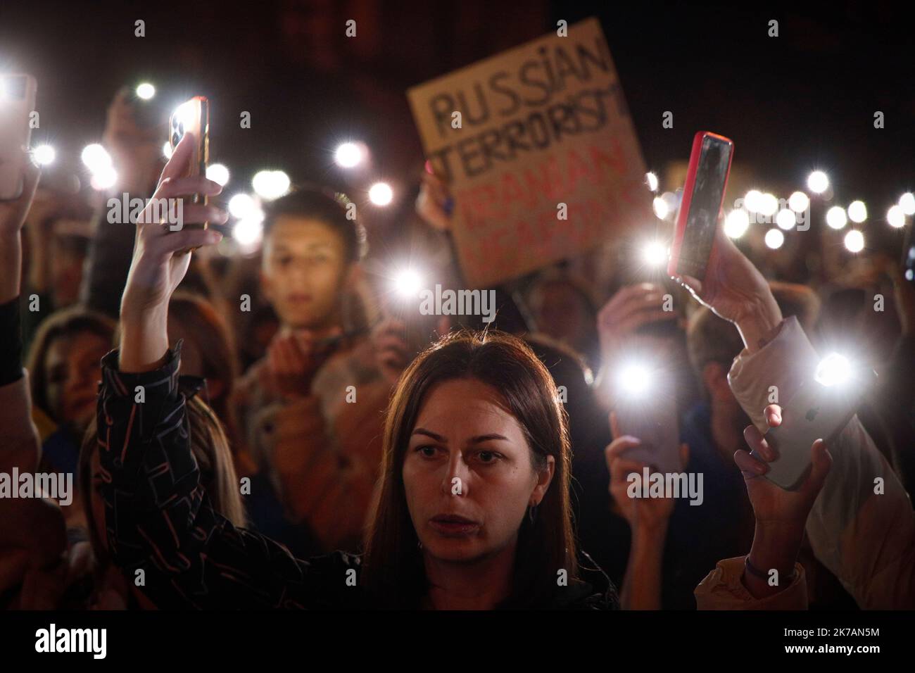 Protesters hold up their phones with flashlights lit during a protest ...