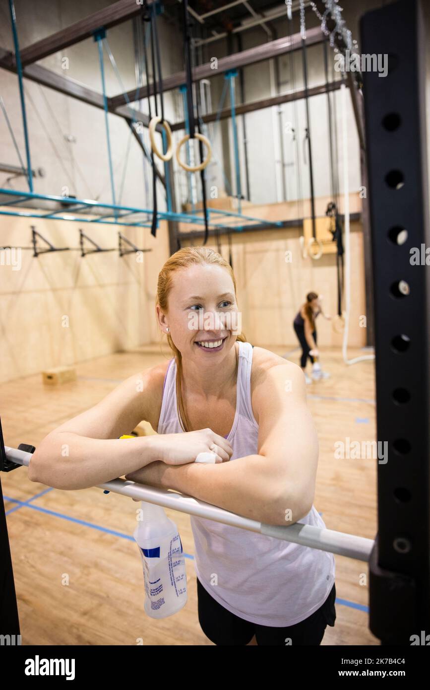 Portrait happy woman with spray cleaner leaning on gym barbell Stock ...