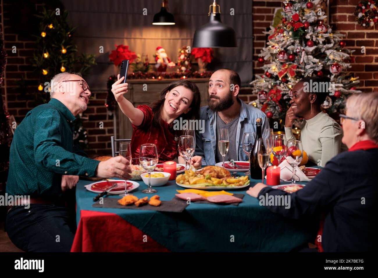 Woman taking smartphone selfie of family christmas celebration, friends ...