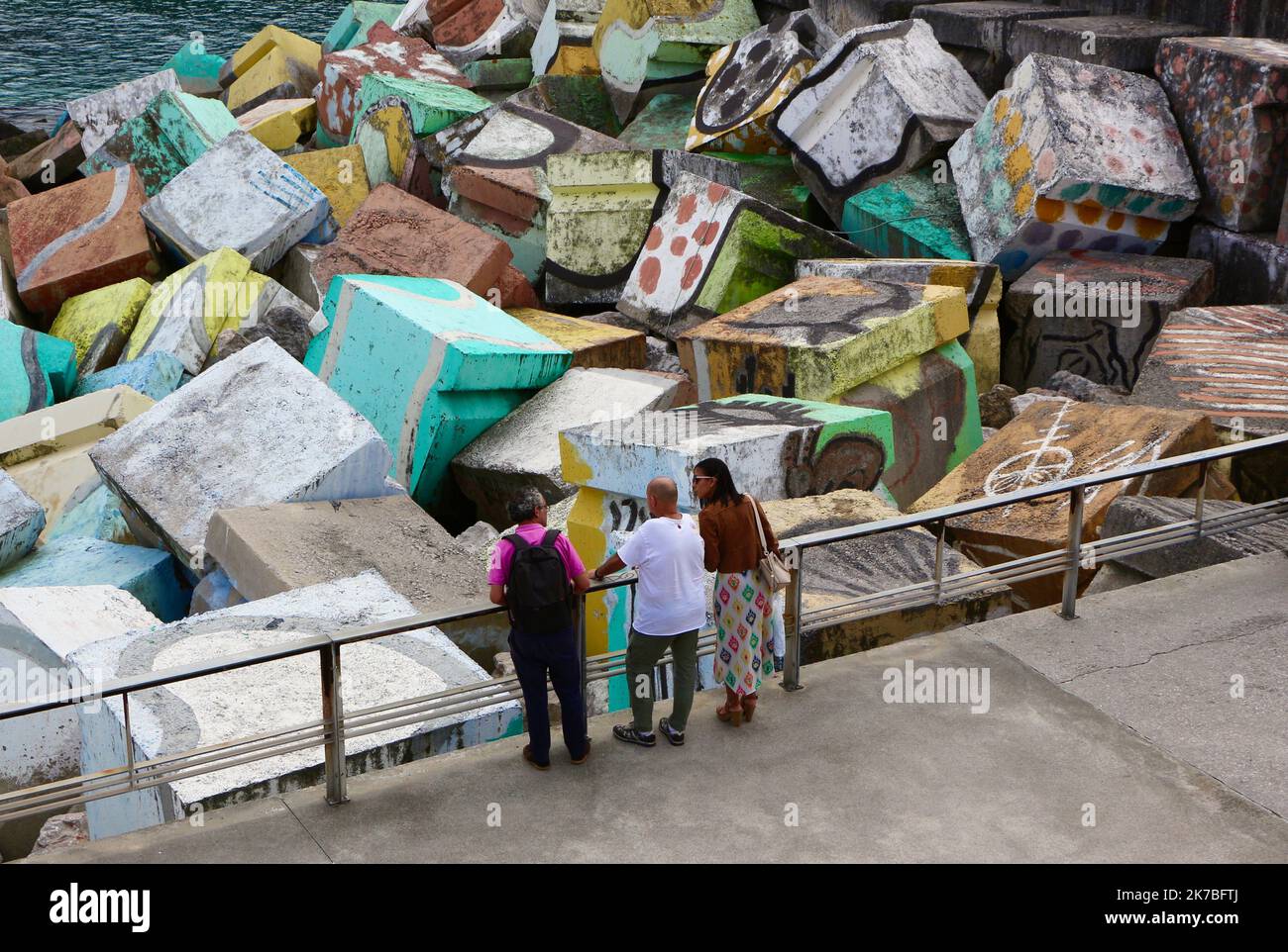 Three people looking at the wave dissipating concrete blocks Cubes of ...
