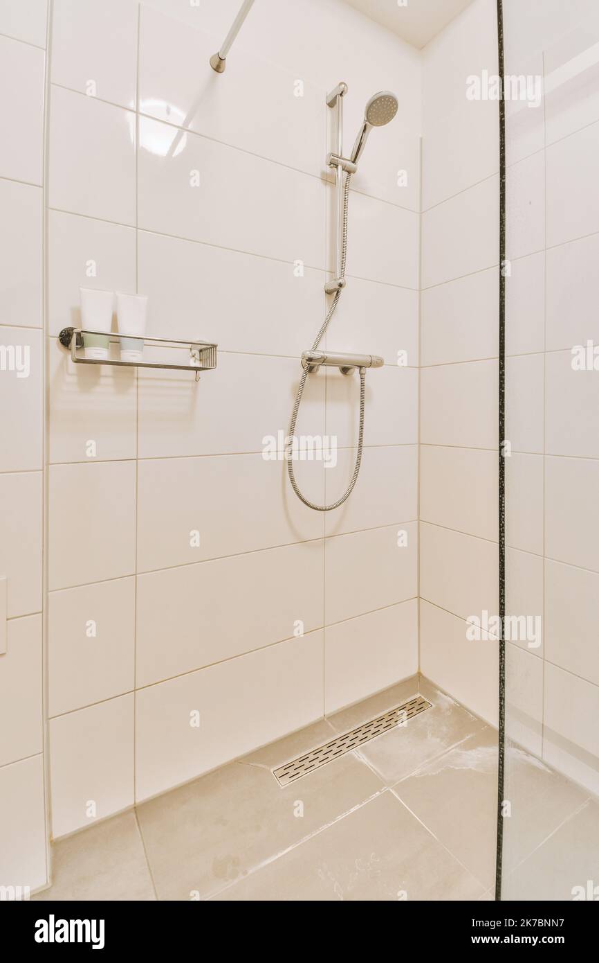 Shower faucets attached to tiled wall near glass partition and ...