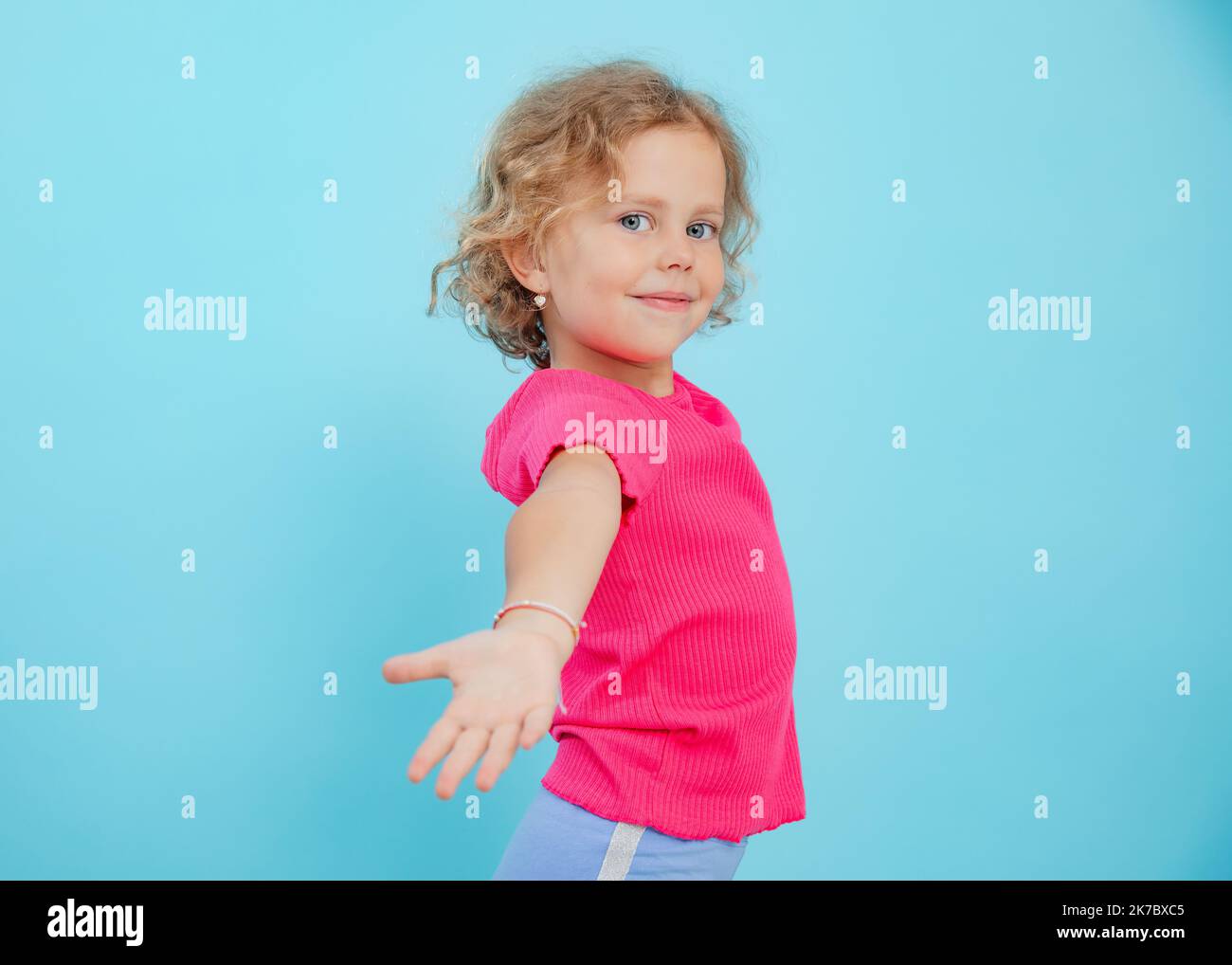 Nice little girl invite people and lend outstretched palm on empty blue ...