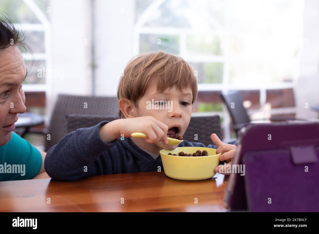 Little boy sit on chair at table and with interest watch cartoon on ...