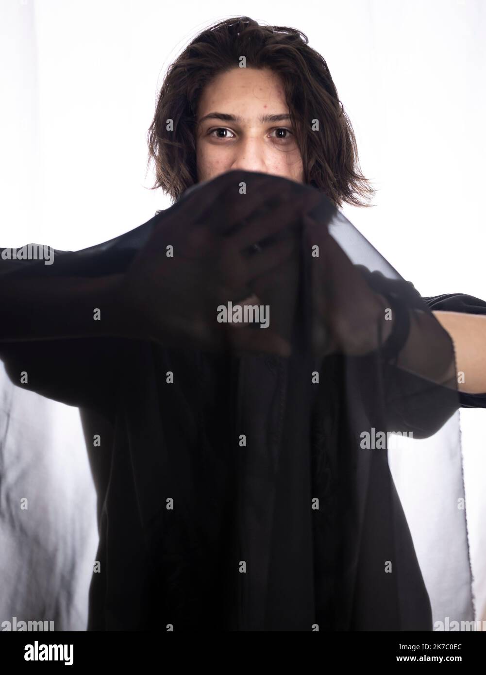 Studio portrait of young man with black transparent fabric in motion ...