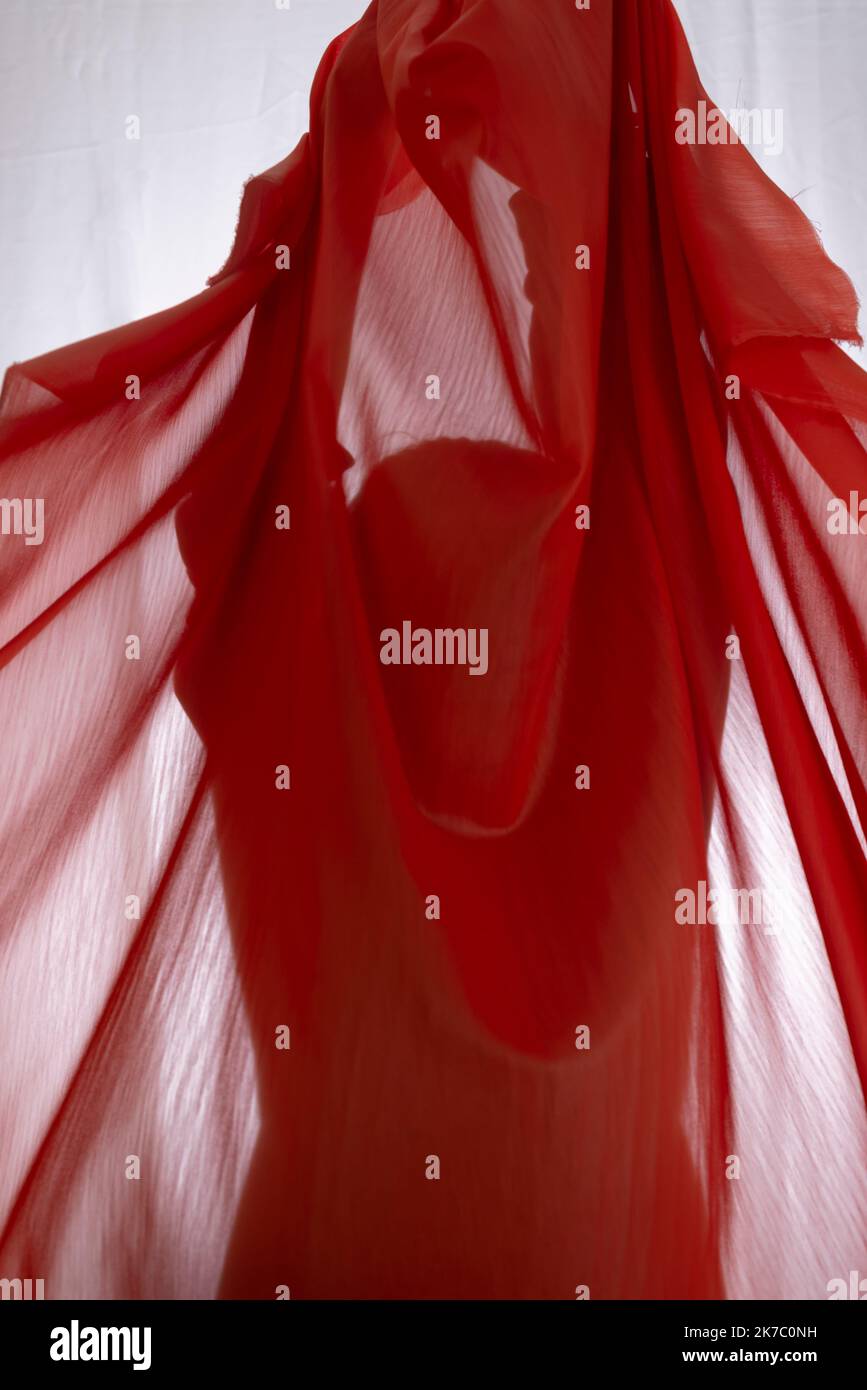Young man with red transparent fabric in motion against white ...