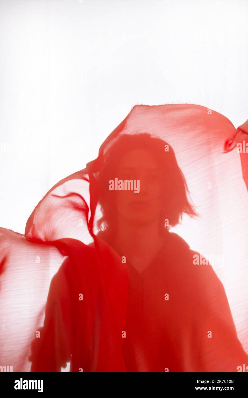 Young man with red transparent fabric in motion against white ...