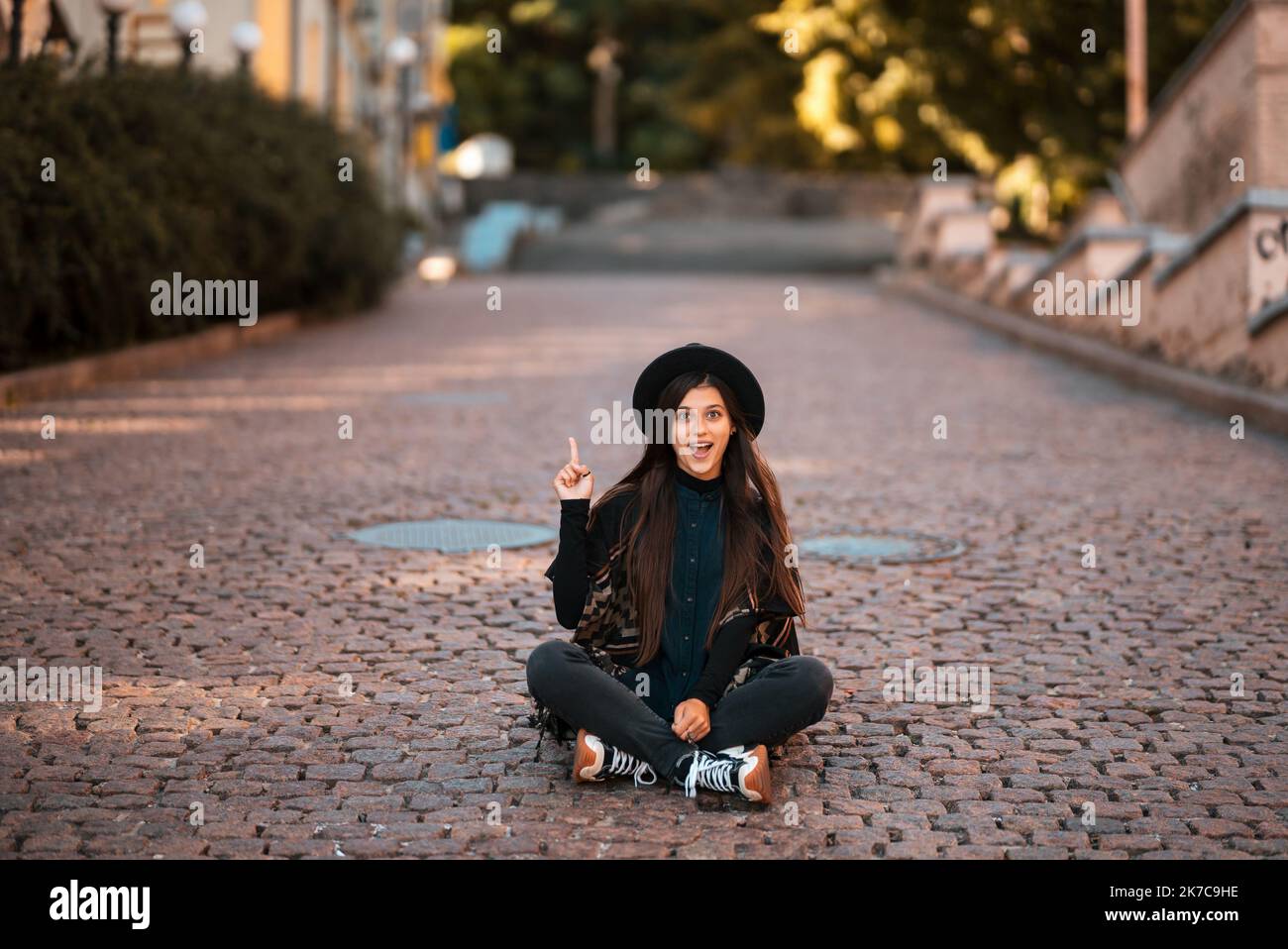 Young woman sitting at city show finger up, new idea Stock Photo - Alamy
