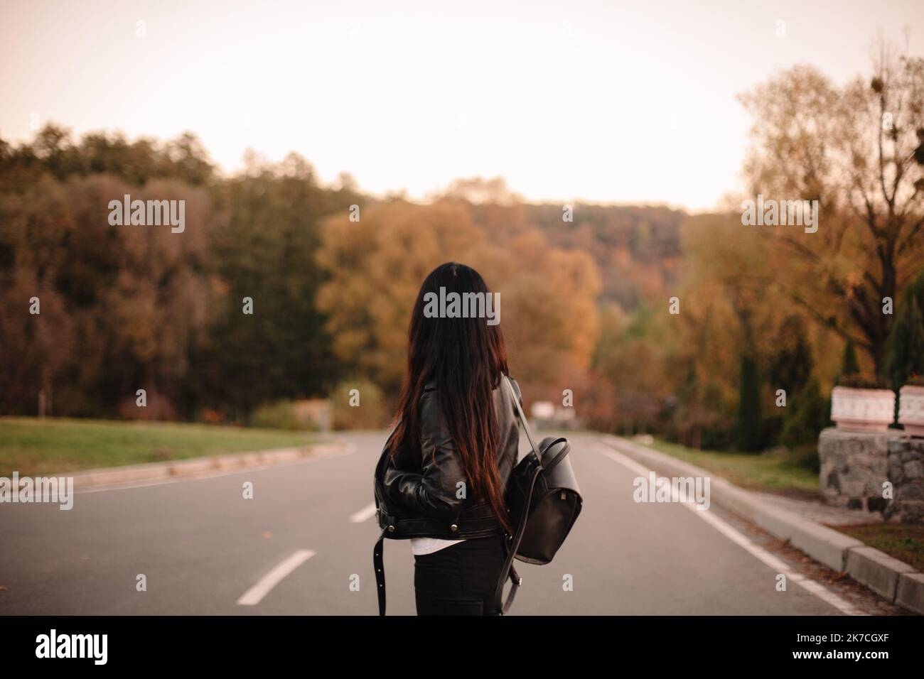 Back view of young female traveler wearing leather jacket and backpack ...